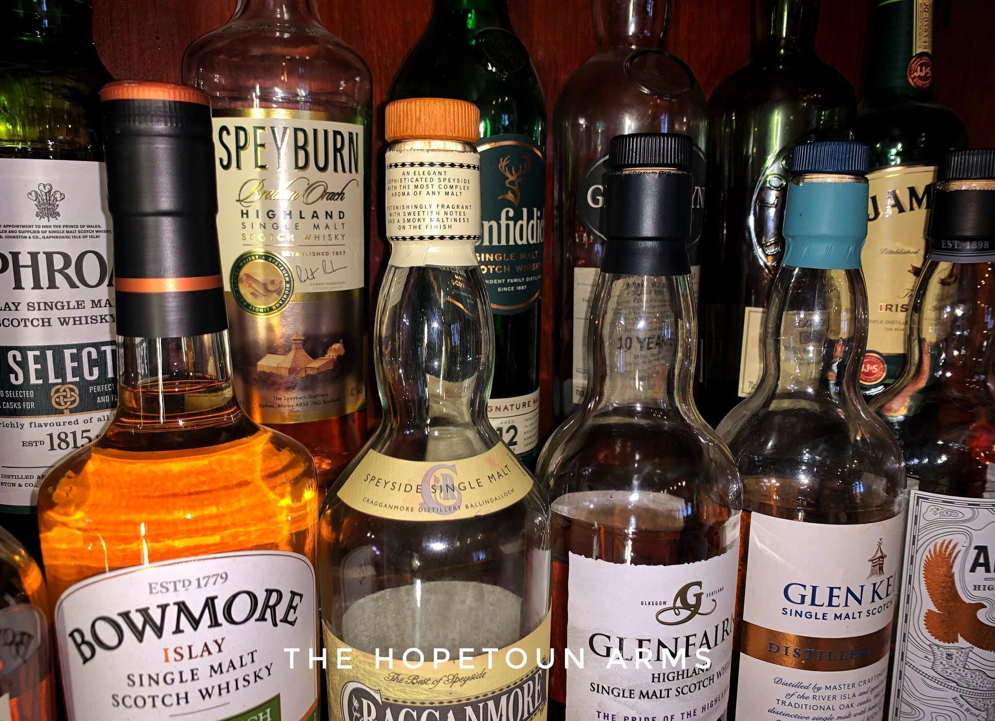 Diversas garrafas de whisky escocês single malt expostas numa prateleira.