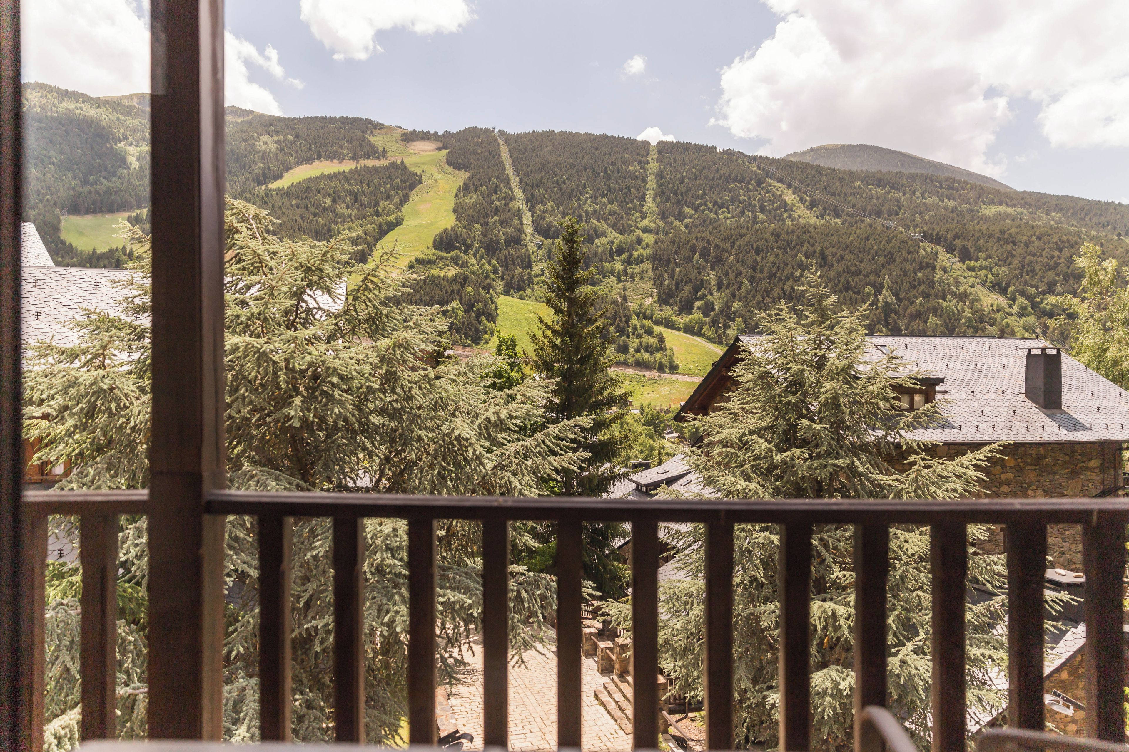Vista de varanda com paisagem montanhosa e pista de esqui.