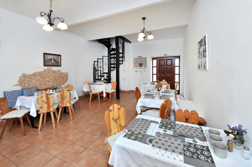 Uma sala de jantar com várias mesas e cadeiras, uma escada e uma parede decorada com quadros.