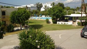 Uma área residencial com piscina, um carro estacionado e um edifício de fachada branca.