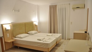 Quarto de hotel com duas camas, uma mesa e uma cadeira.