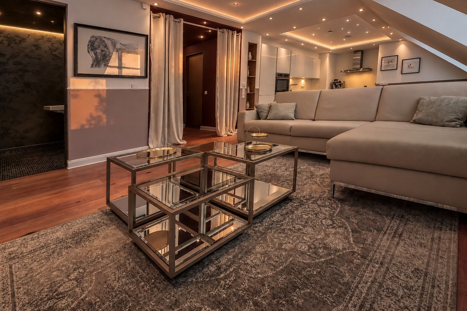 Uma sala de estar moderna com uma mesa de centro de vidro, um sofá bege e um tapete estampado.