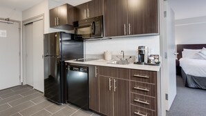 Uma cozinha compacta equipada com geladeira, micro-ondas, cafeteira e lava-louças.