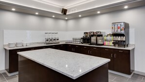 Uma cozinha moderna com armários escuros, uma ilha grande de mármore e uma máquina de café.