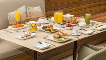 Um buffet de café da manhã com diversos pratos e bebidas sobre uma mesa em um ambiente acolhedor.