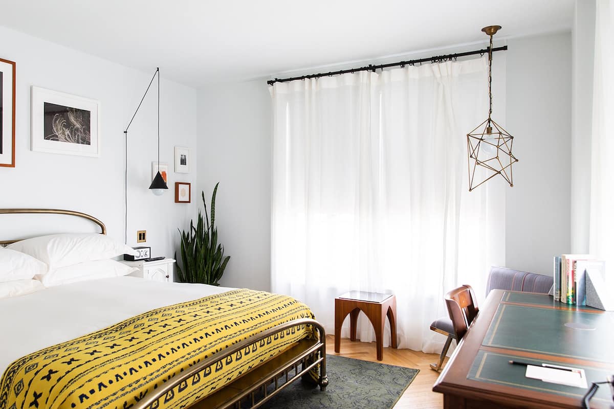 Quarto moderno com cama grande, mesa de cabeceira e escrivaninha com cadeira.