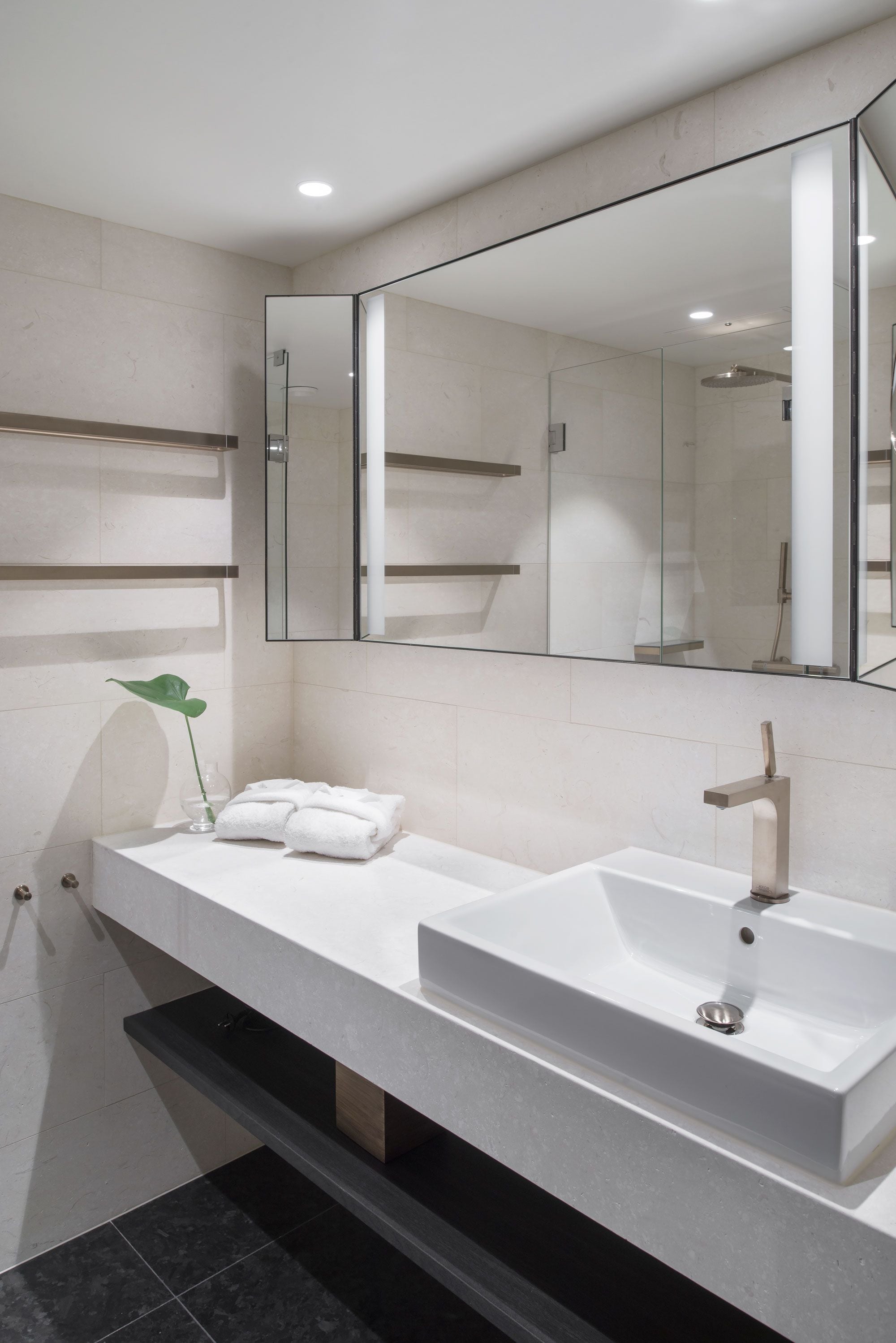 Casa de banho moderna com um espelho grande, duas pias e um porta-toalhas.