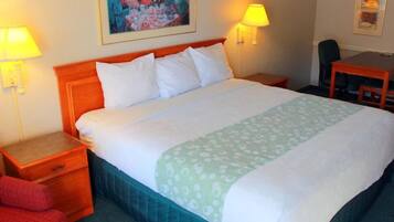 Quarto de hotel com cama grande, duas mesas de cabeceira, escrivaninha e cadeiras.