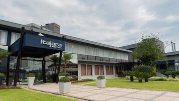 Um hotel moderno com entrada coberta, área de estar ao ar livre e paisagismo bem cuidado.