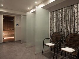Uma área de espera moderna com duas bancadas de madeira, divisória de vidro e parede com papel de parede de bétulas.
