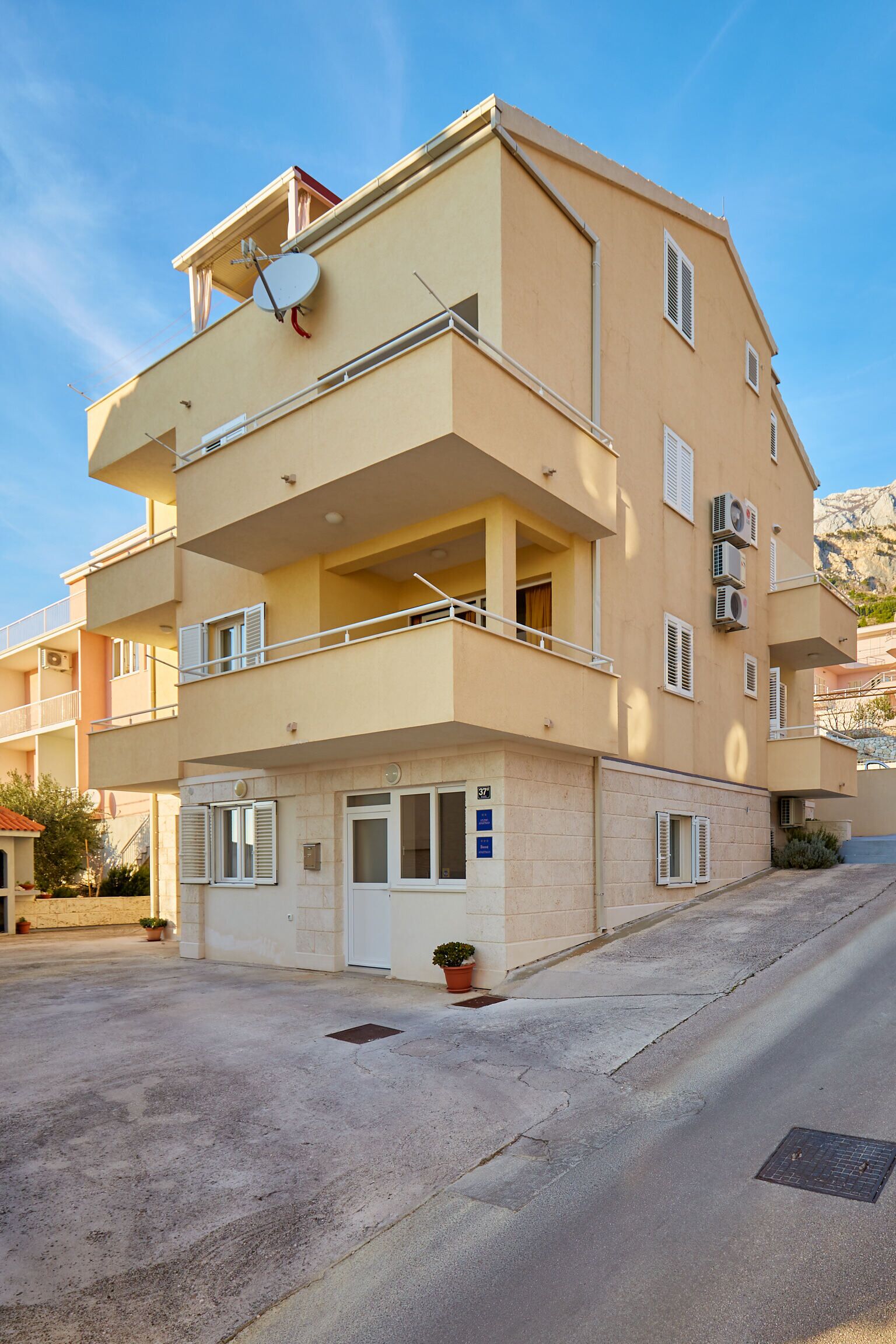 Um edifício residencial de vários andares com varandas, aparelhos de ar condicionado e uma antena parabólica.