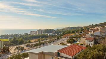 Uma área residencial costeira com edifícios, uma estrada e vista para o mar.