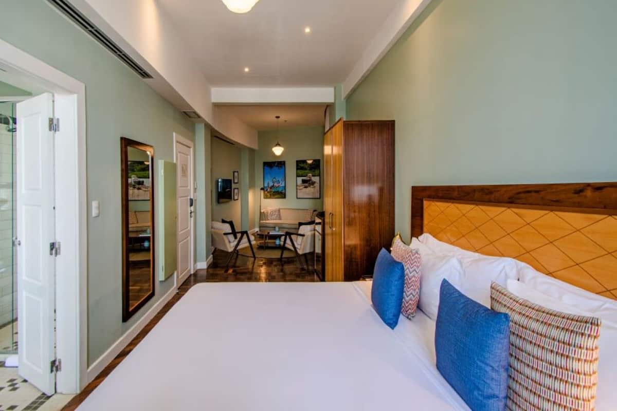 Quarto espaçoso com uma cama grande, cabeceira de madeira e vista para a sala de jantar.
