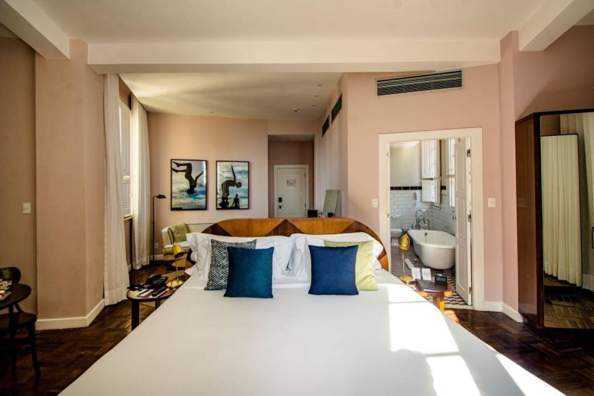 Quarto espaçoso com cama grande, cabeceira de madeira e vista para o banheiro.