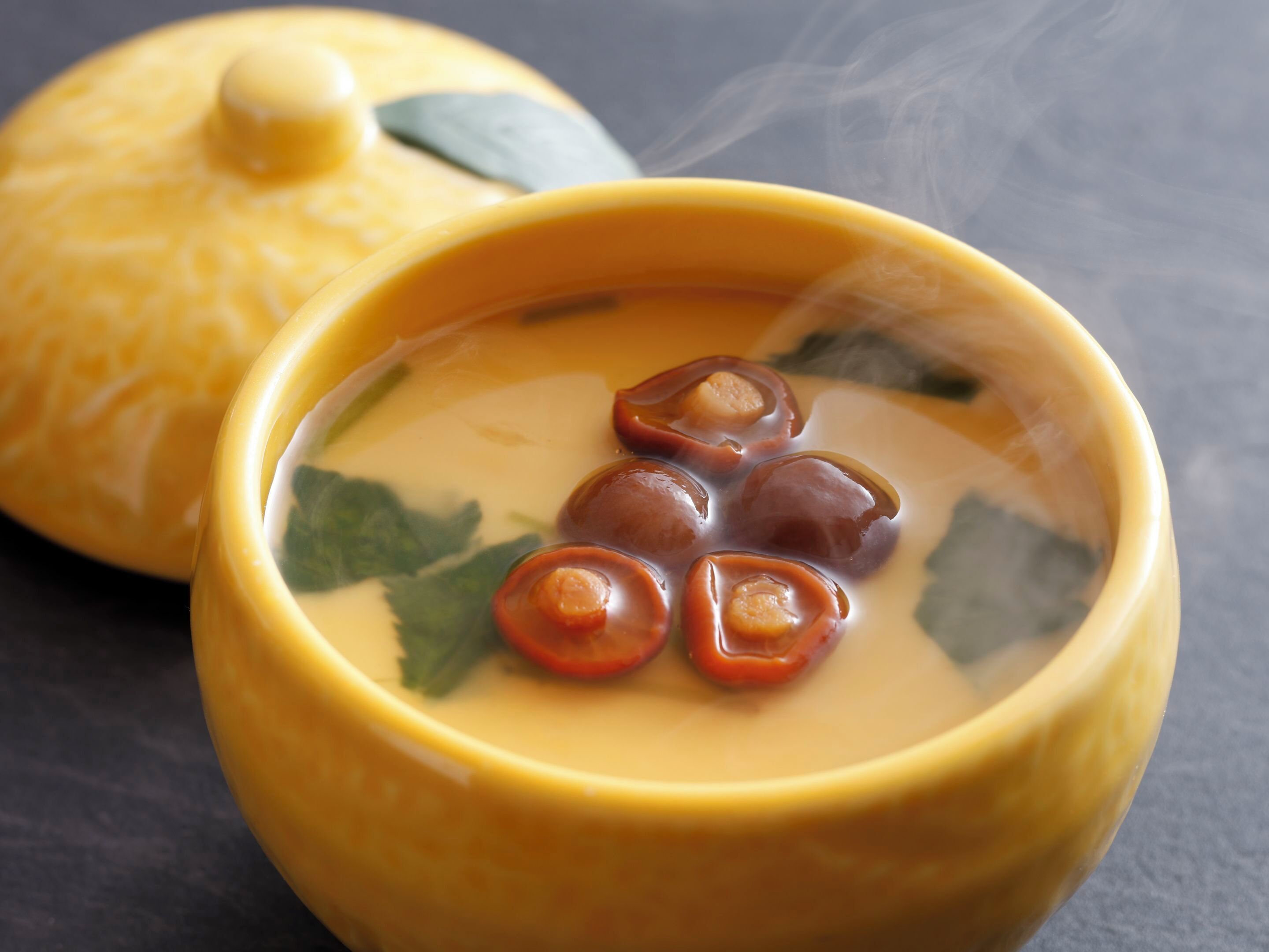 Uma tigela de sopa com tampa e vapor subindo.