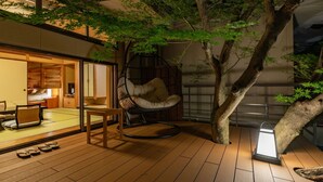 Um quarto japonês tradicional com piso de tatame, uma cadeira suspensa e um lampião.