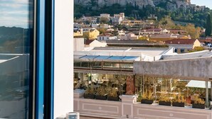 Vista da janela com panorama da cidade, prédios históricos e uma construção antiga imponente numa colina.