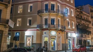 Um hotel com vários andares, varandas, entrada visível e uma placa indicando ser hotel.