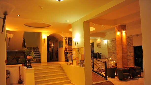 Um interior espaçoso com escadaria para os andares superiores, área de estar com mesas e lareira.