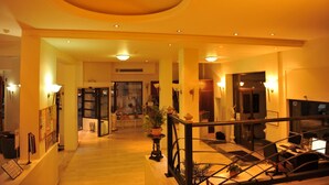 Um hall de hotel com uma escadaria central, uma receção e uma área de estar.