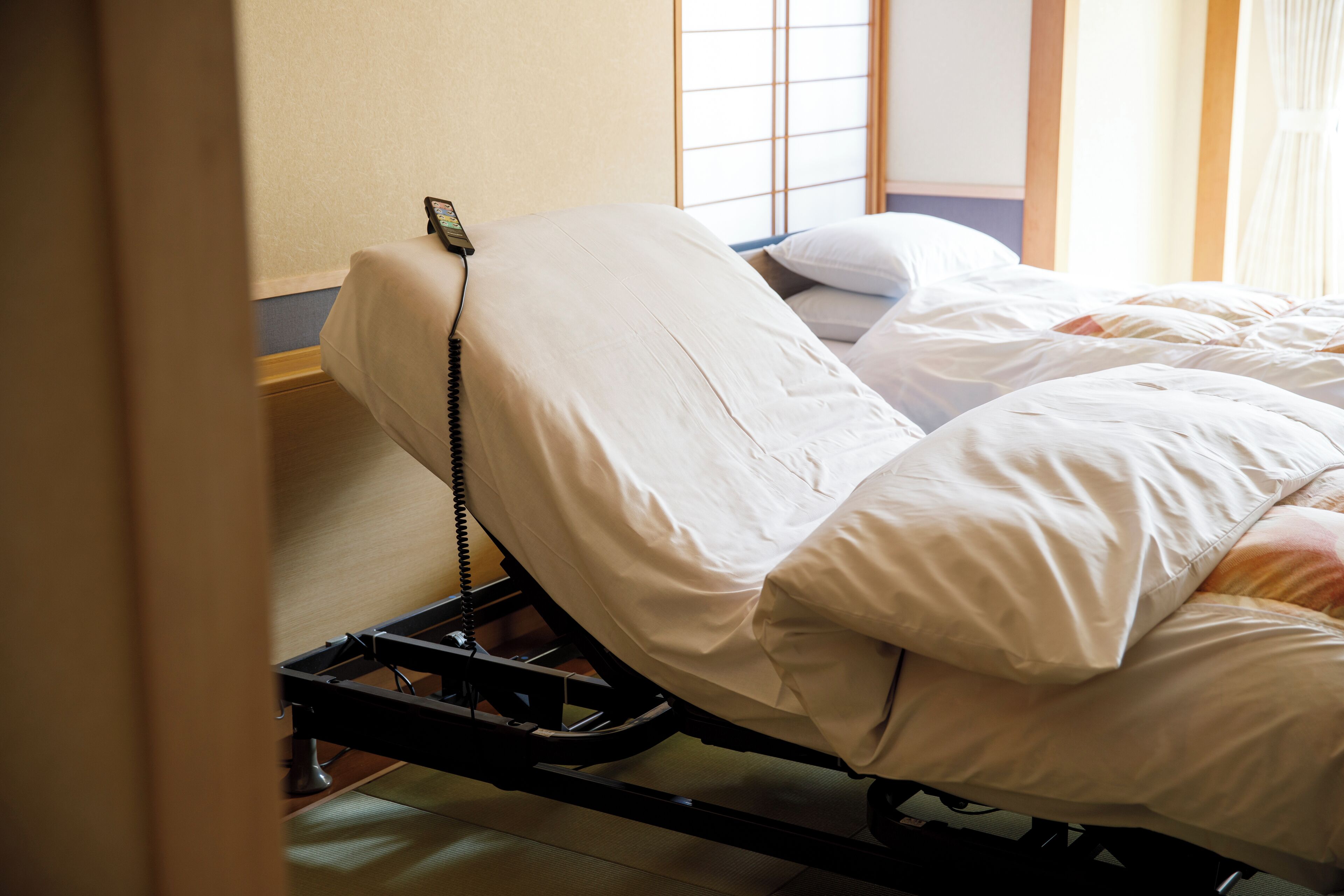 Uma cama de hospital com encosto e telefone.