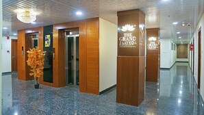 Um saguão de hotel com painéis de madeira, um balcão de recepção e uma placa para 'The Grand Zaayeqa Restaurant'.