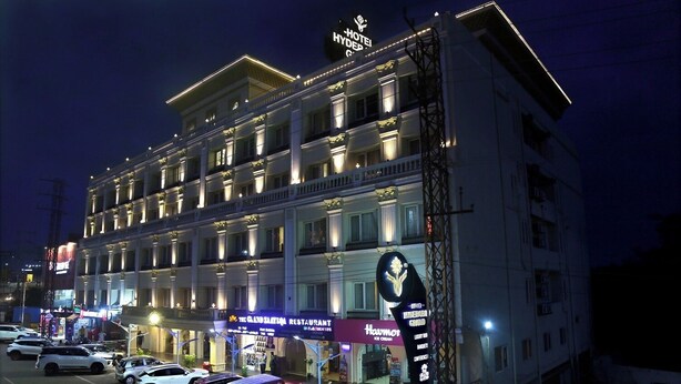 Um hotel de vários andares com estilo arquitetônico clássico, exibindo uma placa chamativa para 'The Grand Hotel' e um restaurante chamado 'The Grand Restaurant'.