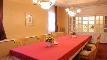 Uma sala de conferências com uma mesa comprida, cadeiras e lustres.
