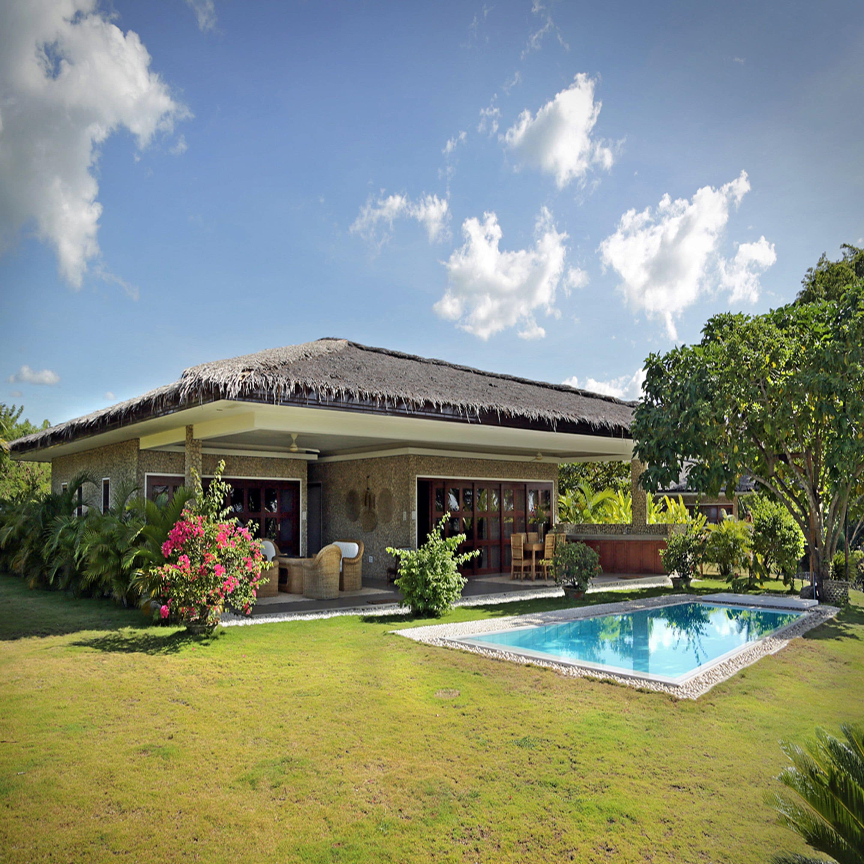 Uma casa com piscina, alpendre coberto e jardim.