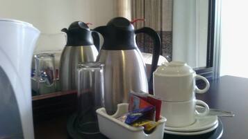 Disposição para o café da manhã, com cafeteira, bule e xícara e pires em uma bandeja.
