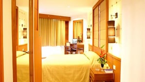 Quarto de hotel com duas camas, uma escrivaninha e uma cadeira.