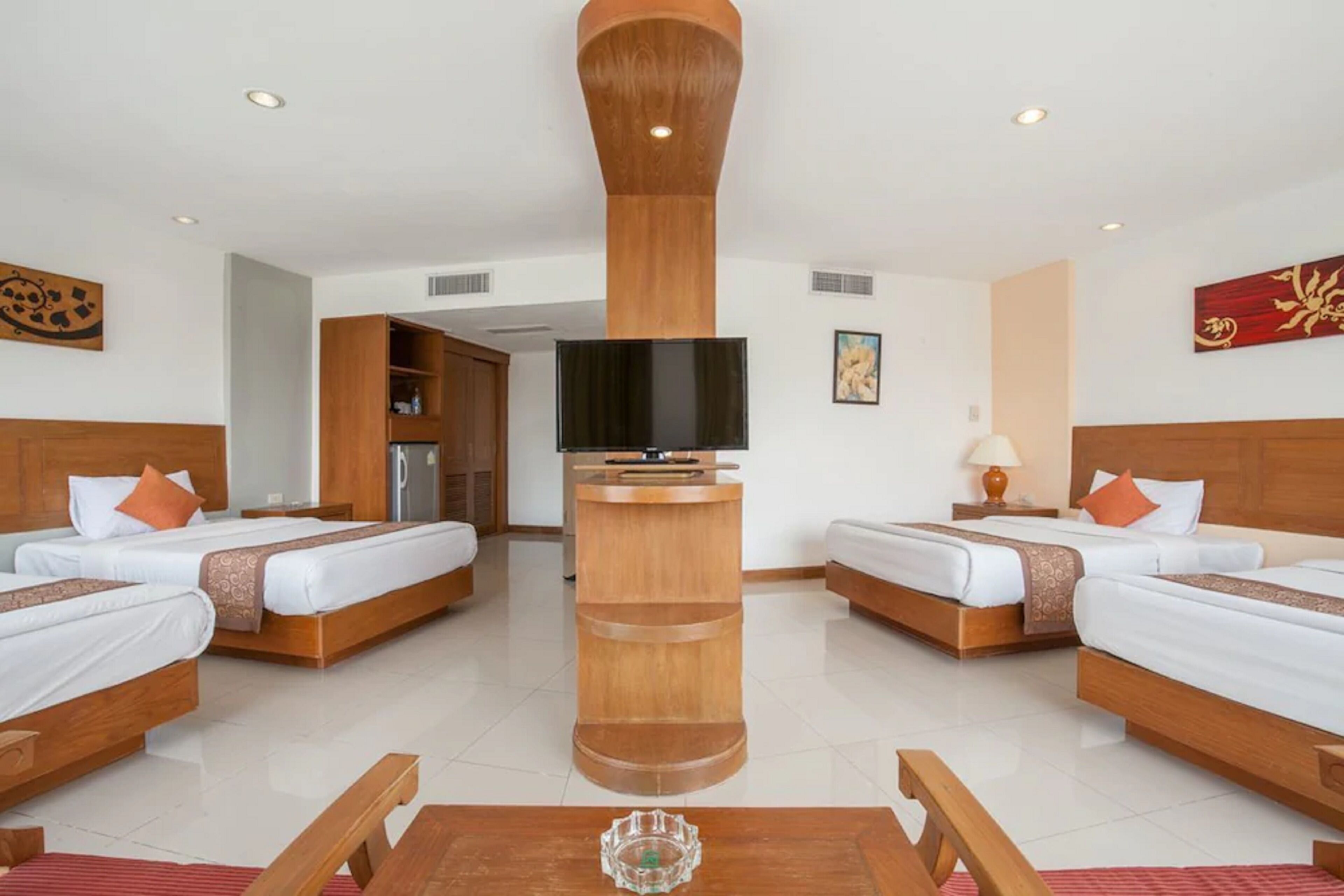 Quarto de hotel com duas camas, uma mesa de centro de madeira, televisão e minibar.
