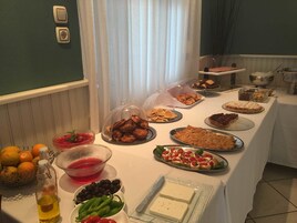 Uma mesa de buffet com diversos alimentos, incluindo doces, frutas e uma garrafa de óleo.