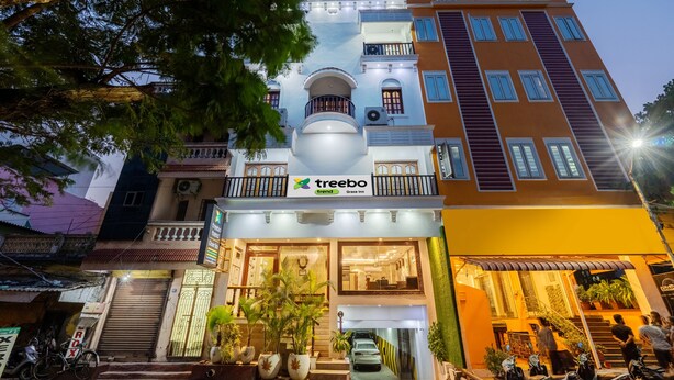 Um edifício de vários andares com um letreiro chamativo 'treebo trend', varandas e uma entrada bem iluminada.