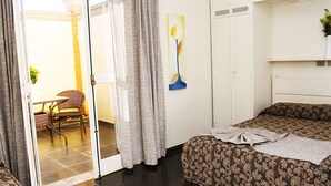 Quarto de hotel com cama, cadeira, mesa e um quadro na parede.