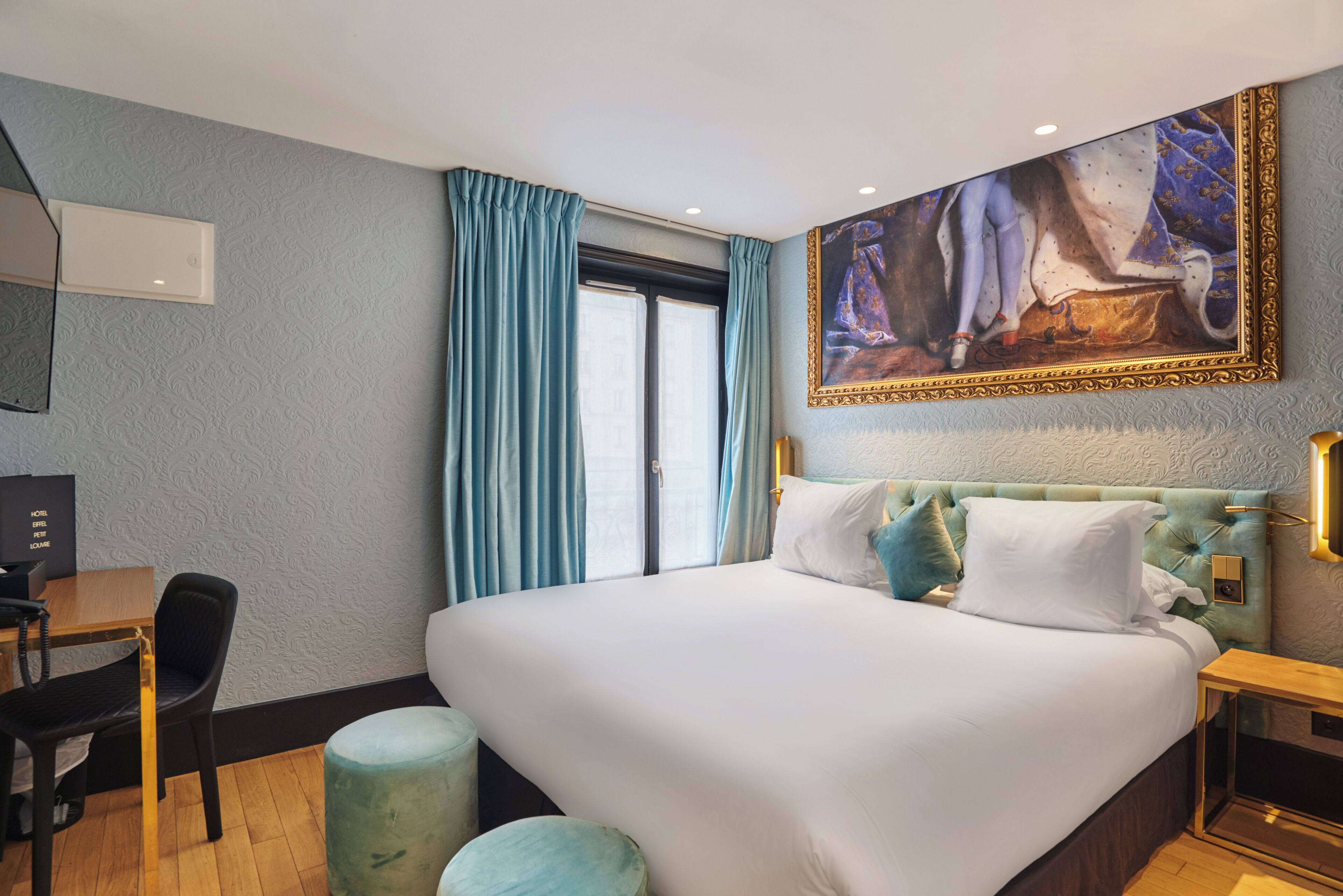 Quarto de hotel com uma cama grande, uma escrivaninha, uma cadeira e um quadro na parede.