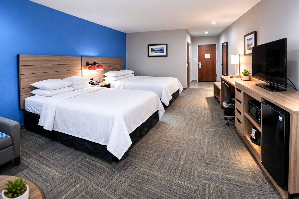 Quarto de hotel com duas camas, televisão, secretária e micro-ondas.