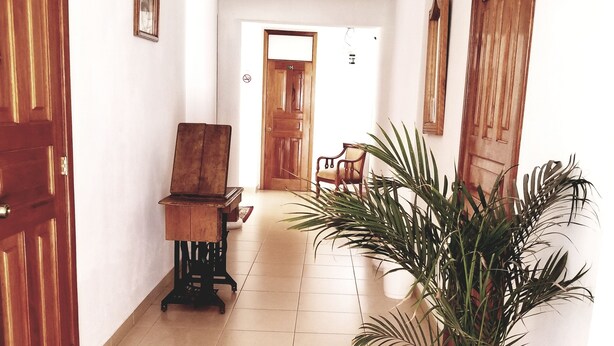 Um corredor com portas de madeira, um piano, uma cadeira e um vaso de planta.