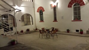 Um pátio com uma mesa redonda e cadeiras, uma escadaria e plantas em vasos.