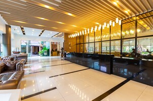Um hall amplo com teto alto, luminárias modernas e uma área de recepção com uma grande janela.