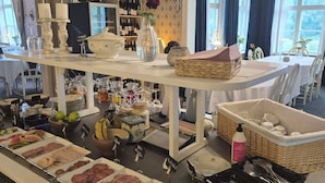 Buffet de café da manhã com diversos alimentos e um espaço para vinhos ao fundo.