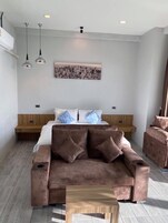 Quarto moderno com uma cama grande, um sofá marrom e uma mesa de centro de madeira.
