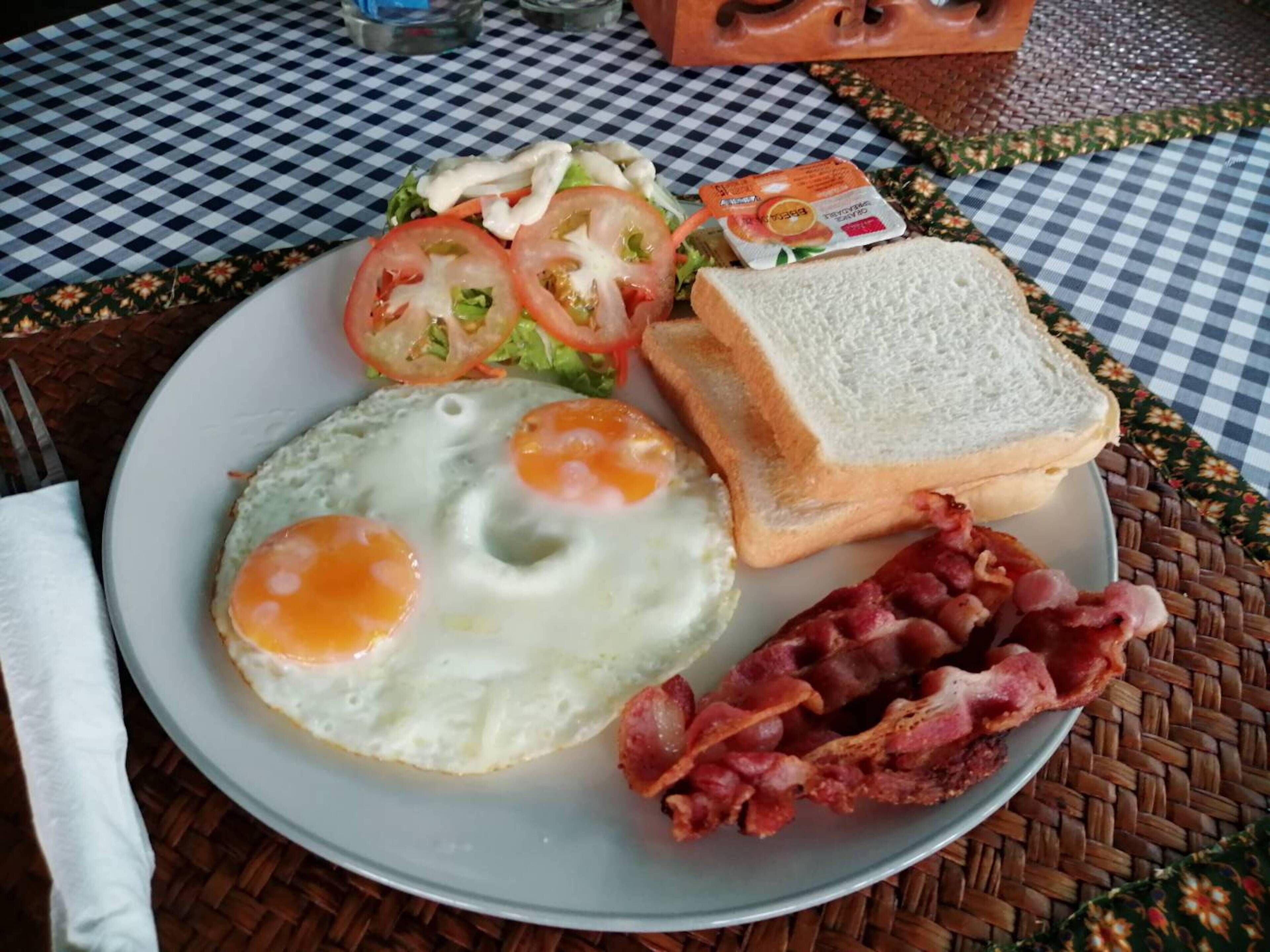 Um prato com ovos, bacon, torradas e salada.