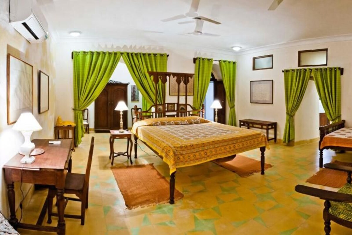 Quarto com cama, escrivaninha, cadeira e sofá.