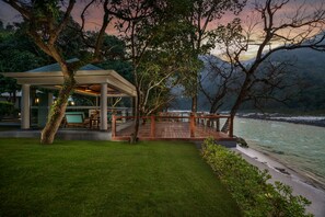Uma casa moderna com fachada de vidro, um deck com vista para a praia e para o oceano.