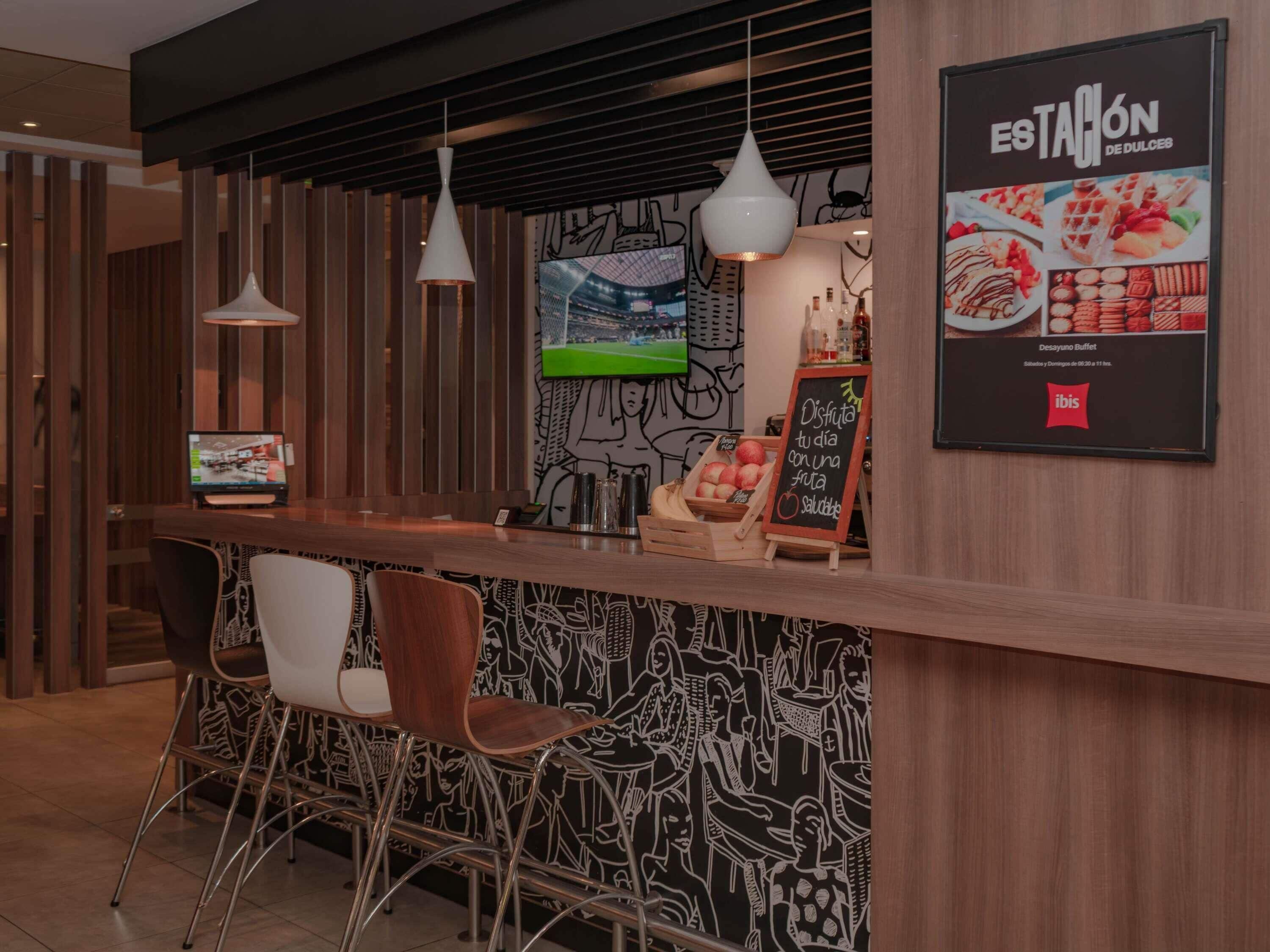 Uma área de bar moderna com painéis de madeira, luminárias pendentes e um cardápio em lousa.