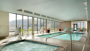 Piscina interior com várias pistas de natação, uma banheira de hidromassagem e áreas de estar com cadeiras.