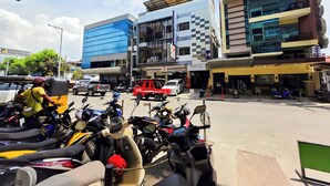 Vista da rua com motocicletas estacionadas, um caminhão vermelho e edifícios modernos com sinalização.