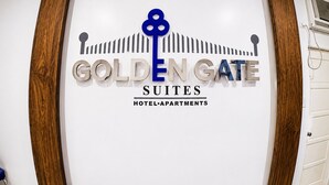 Placa de hotel com o nome 'GOLDENGATE SUITES HOTEL APARTMENTS' e um símbolo de chave.