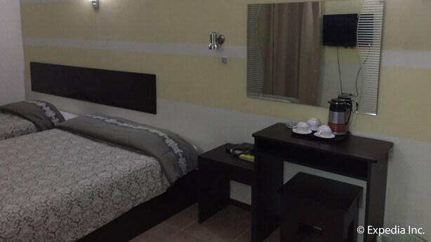 Quarto de hotel com cama, mesa de cabeceira e escrivaninha com espelho.